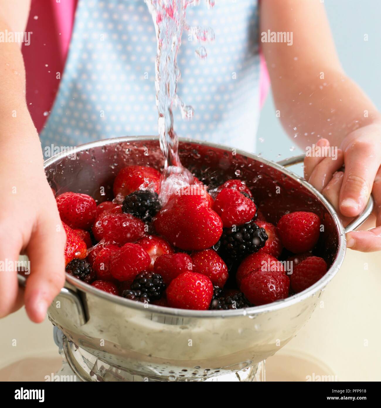 Girl washing fresh strawberries and blackberries in colander Stock ...