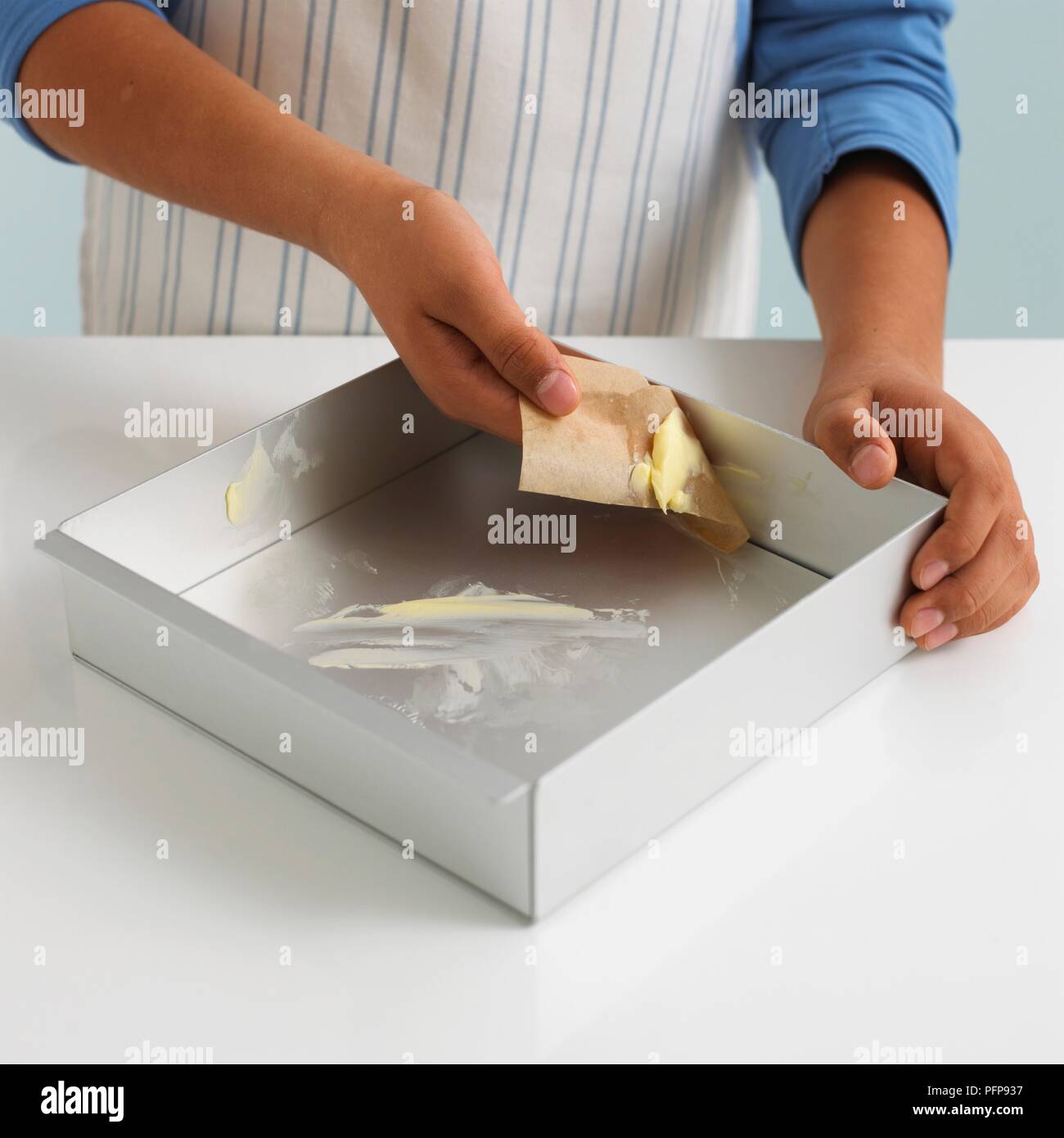 Boy holding butter in piece of wax paper to butter cake tin Stock Photo ...