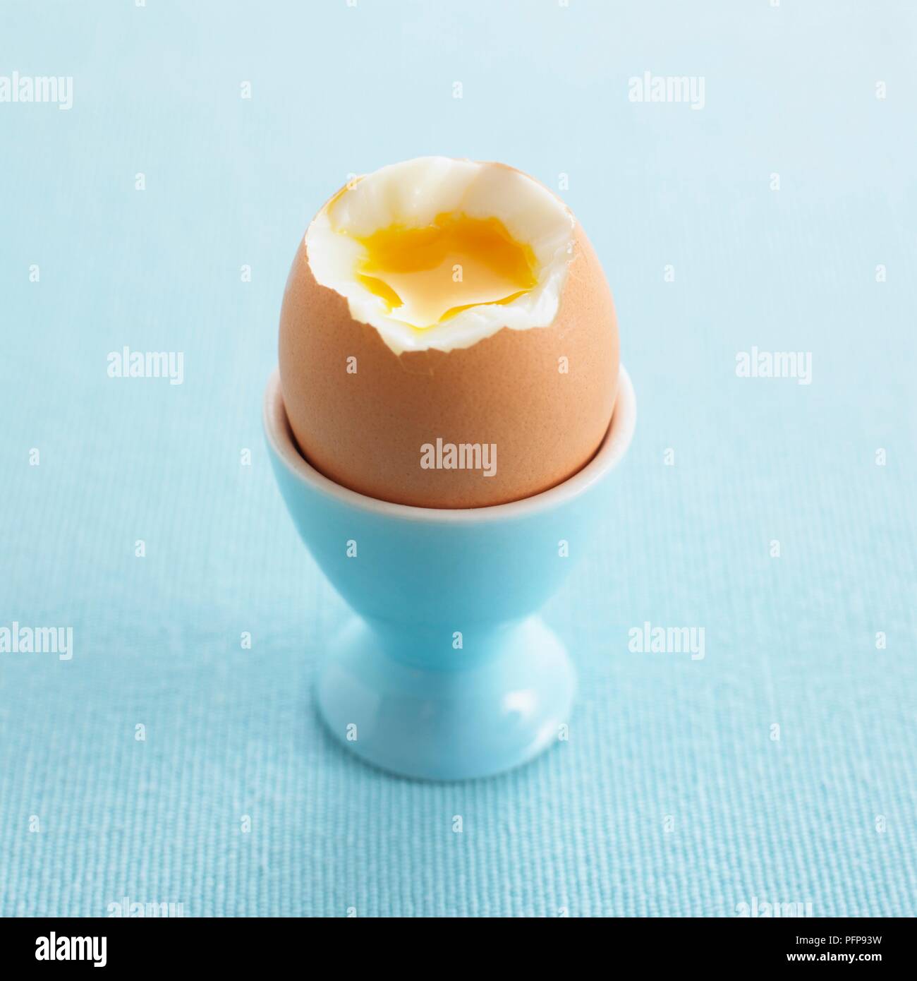 Boiled egg in blue egg cup showing yolk Stock Photo - Alamy