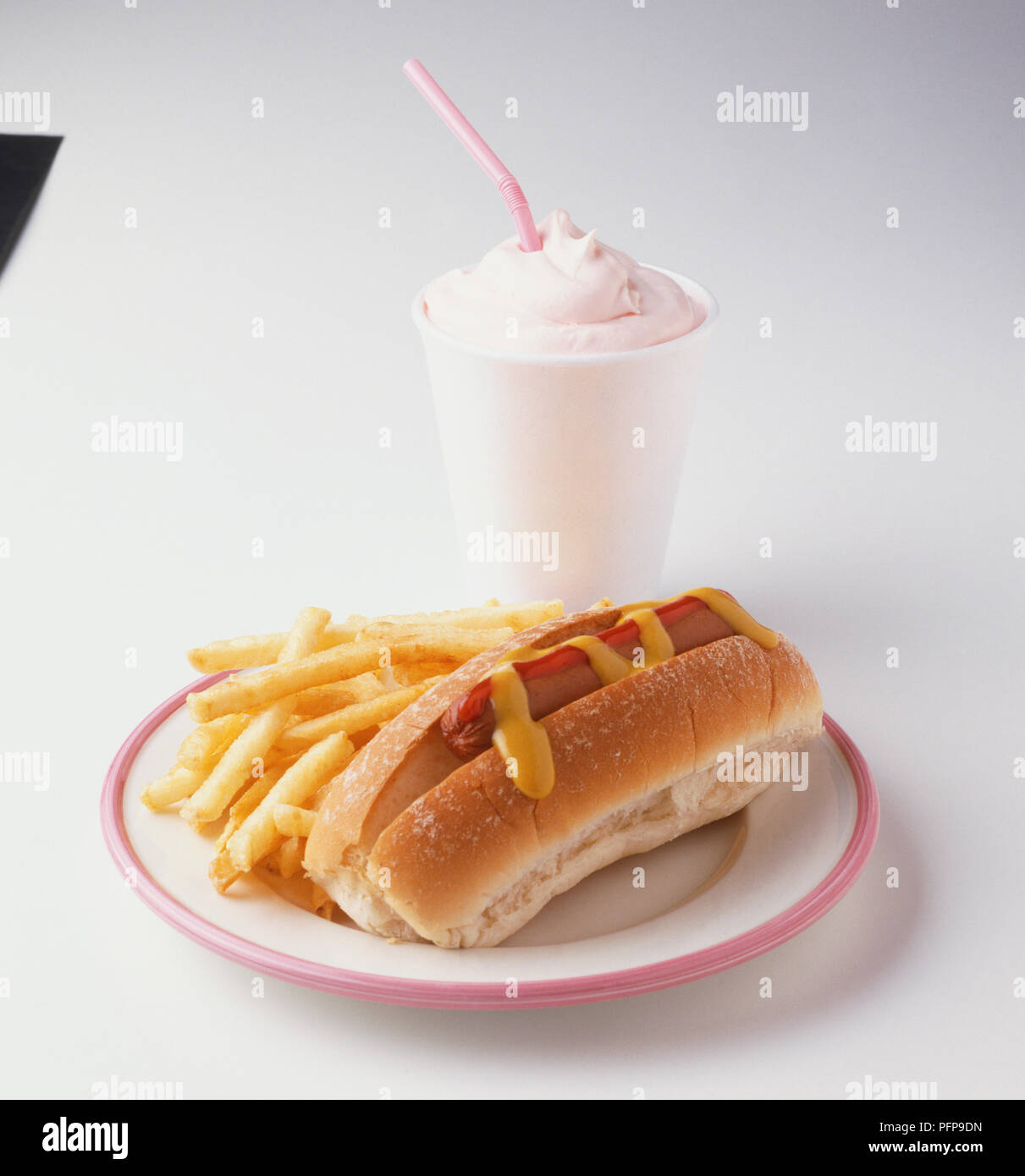 Hot dog with mustard and chips and milkshake on side Stock Photo - Alamy