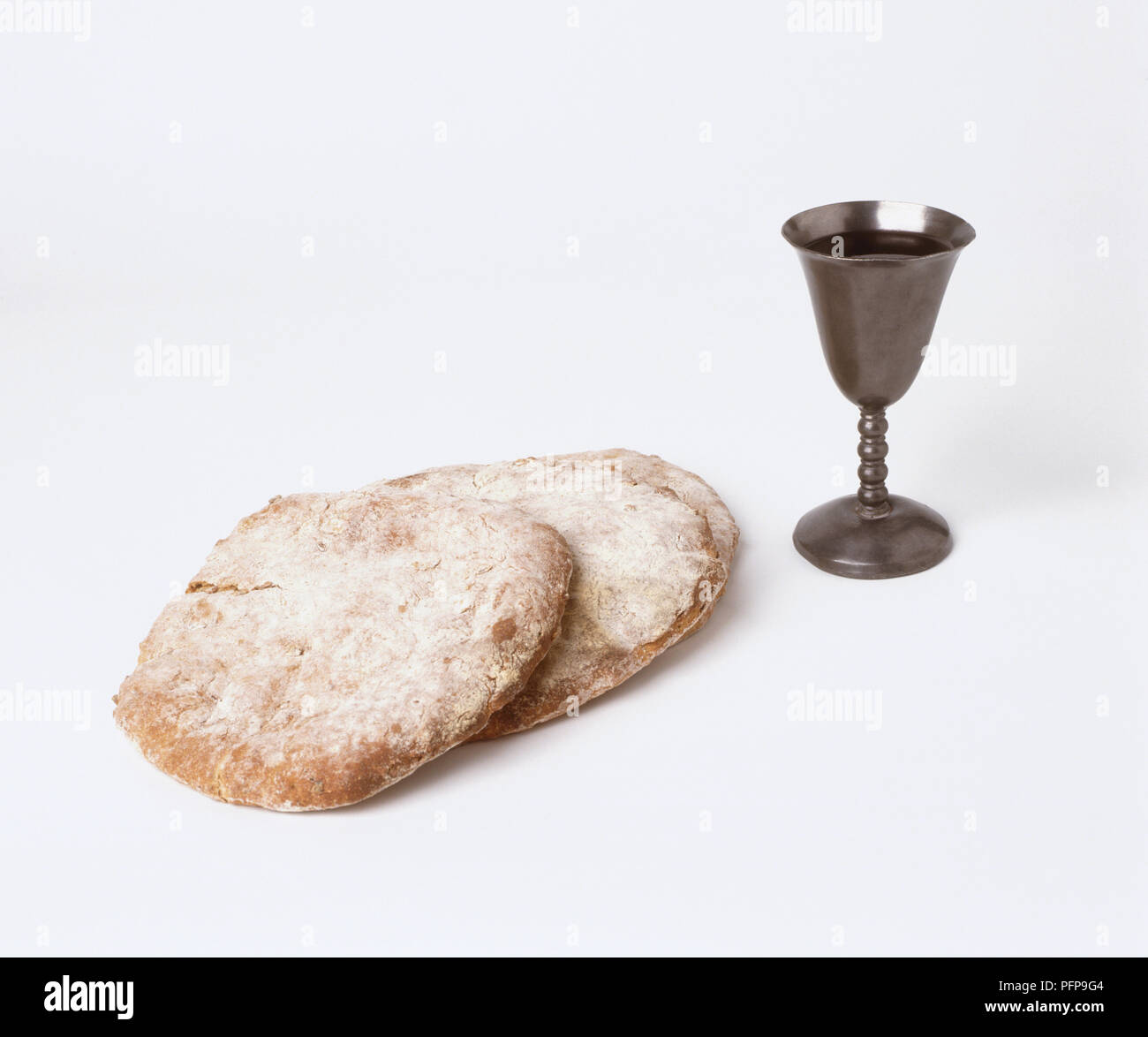 Medieval flatbreads known as bread plates, and pewter goblet, close-up ...