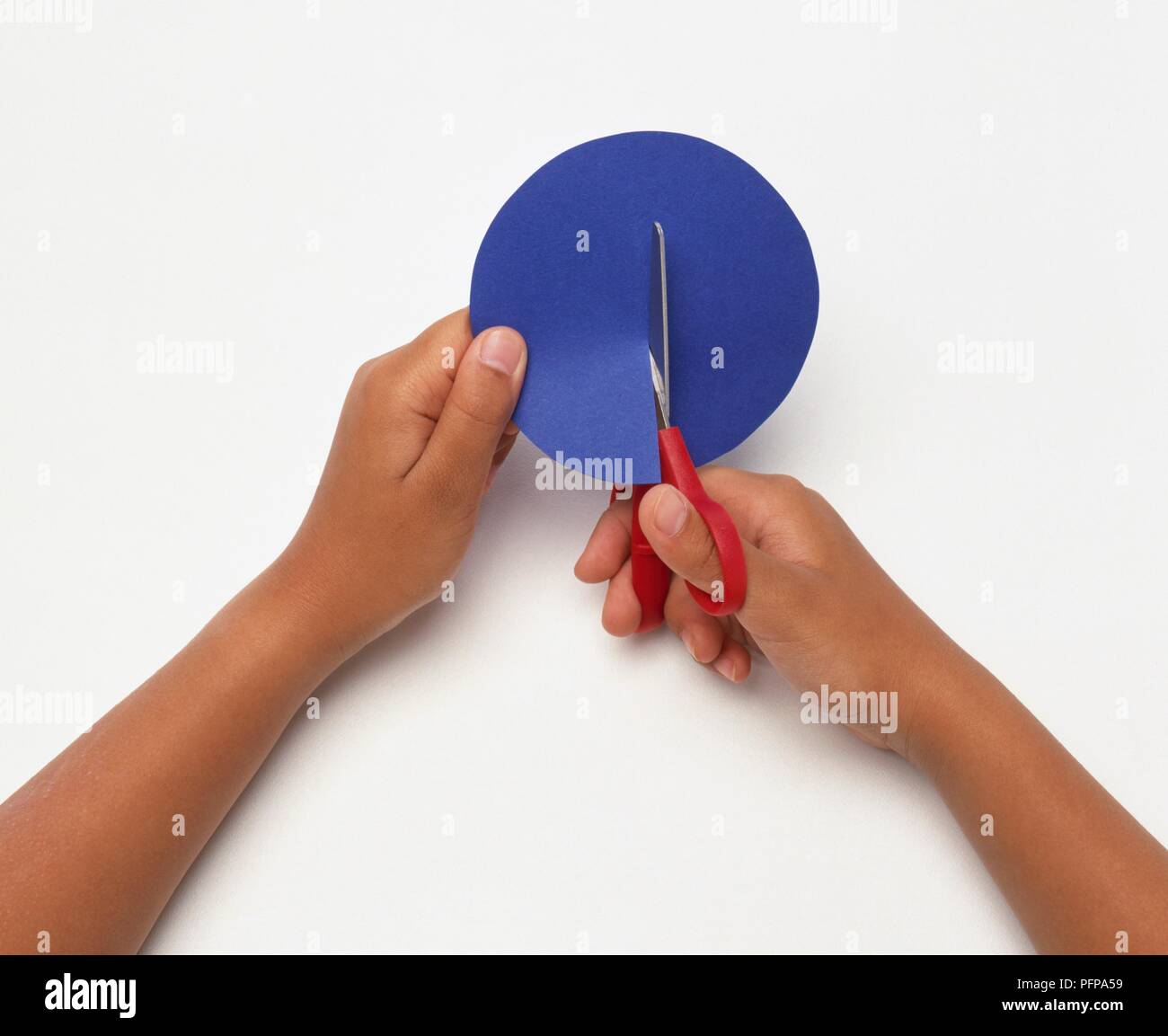 Boy's hands cutting blue cardboard circle in half, using scissors Stock ...
