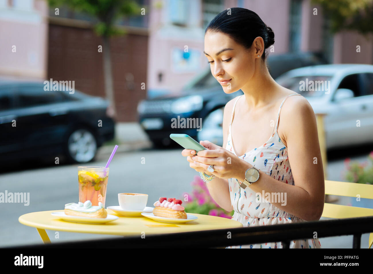 Calm woman typing messages and enjoying her tasty dessert Stock Photo ...