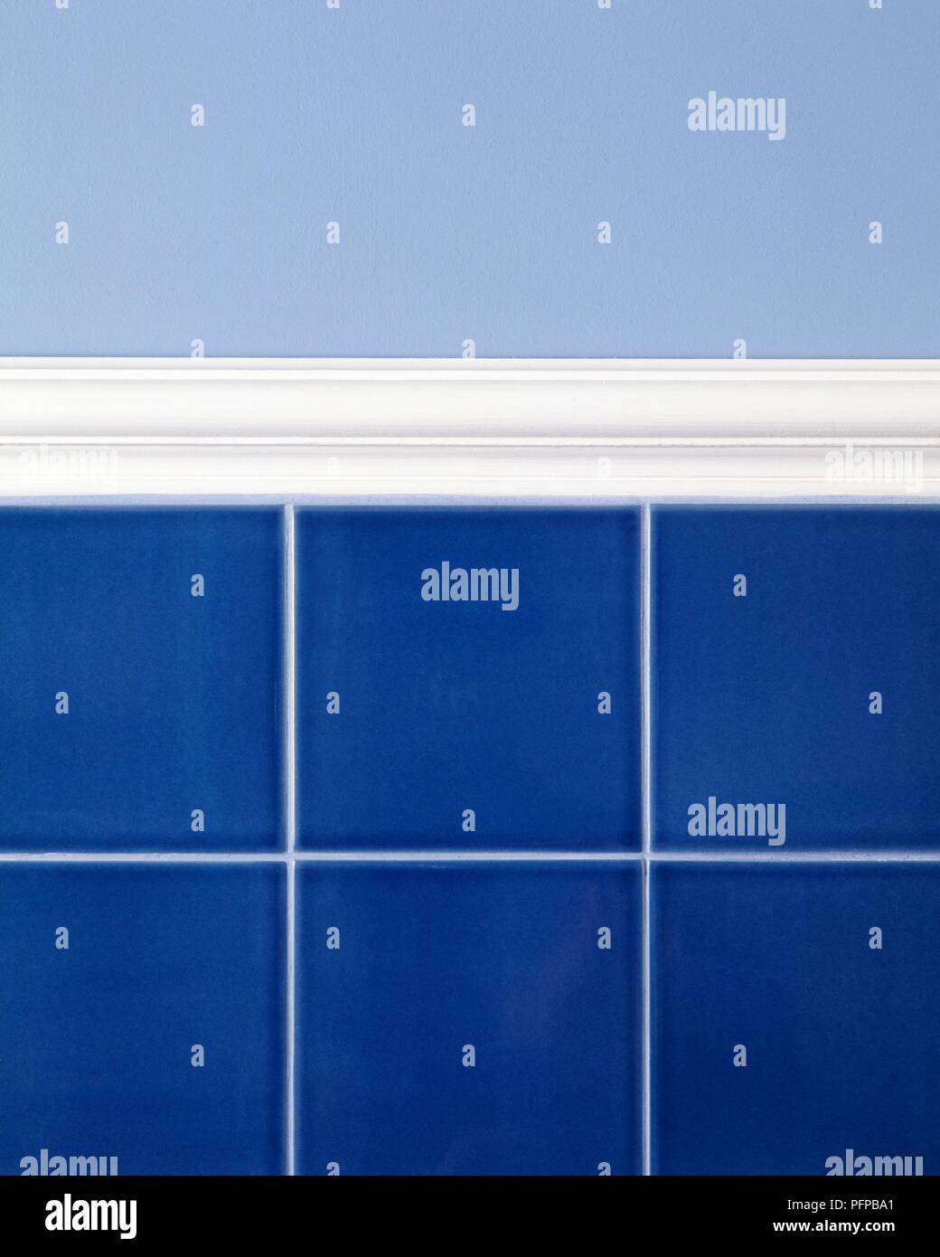 Blue tiles with blue grout, below white moulding and blue wall, close ...