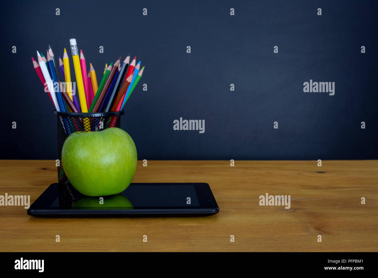 Back to school background with tablet, pencils and green apple over ...