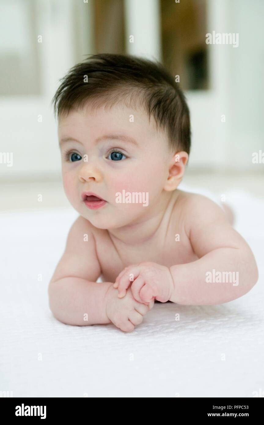Baby girl lying on front, head raised Stock Photo - Alamy