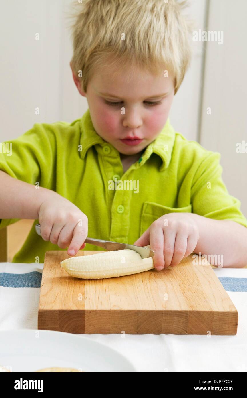 Boy slicing banana with knife Stock Photo - Alamy