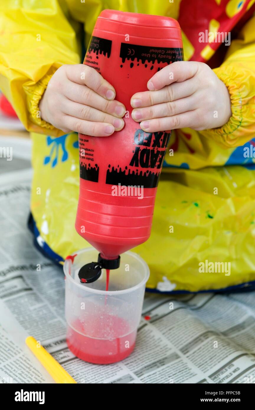 Child's hands squeezing tube of red paint into pot Stock Photo - Alamy