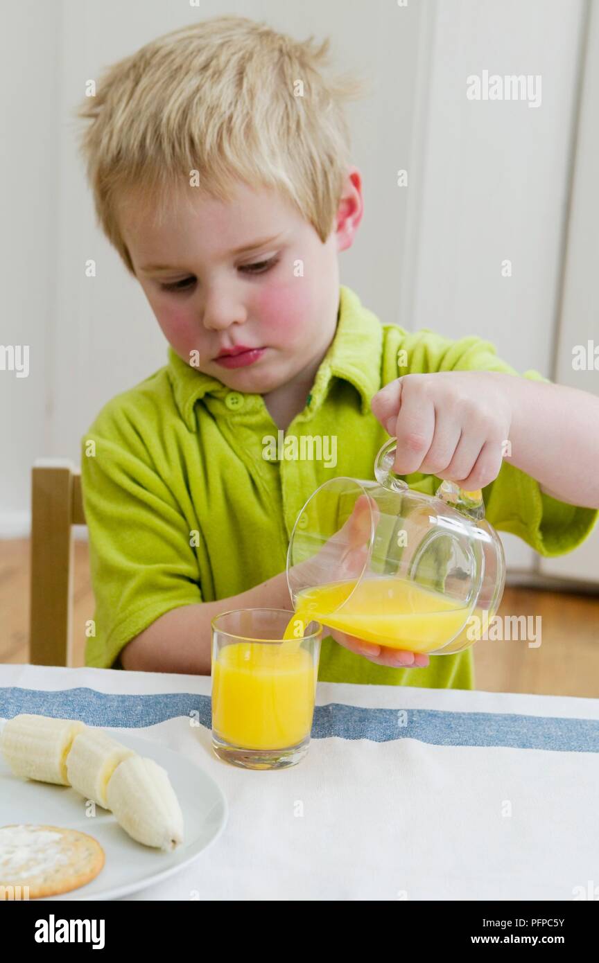 Boy pouring orange juice from jug into glass Stock Photo - Alamy