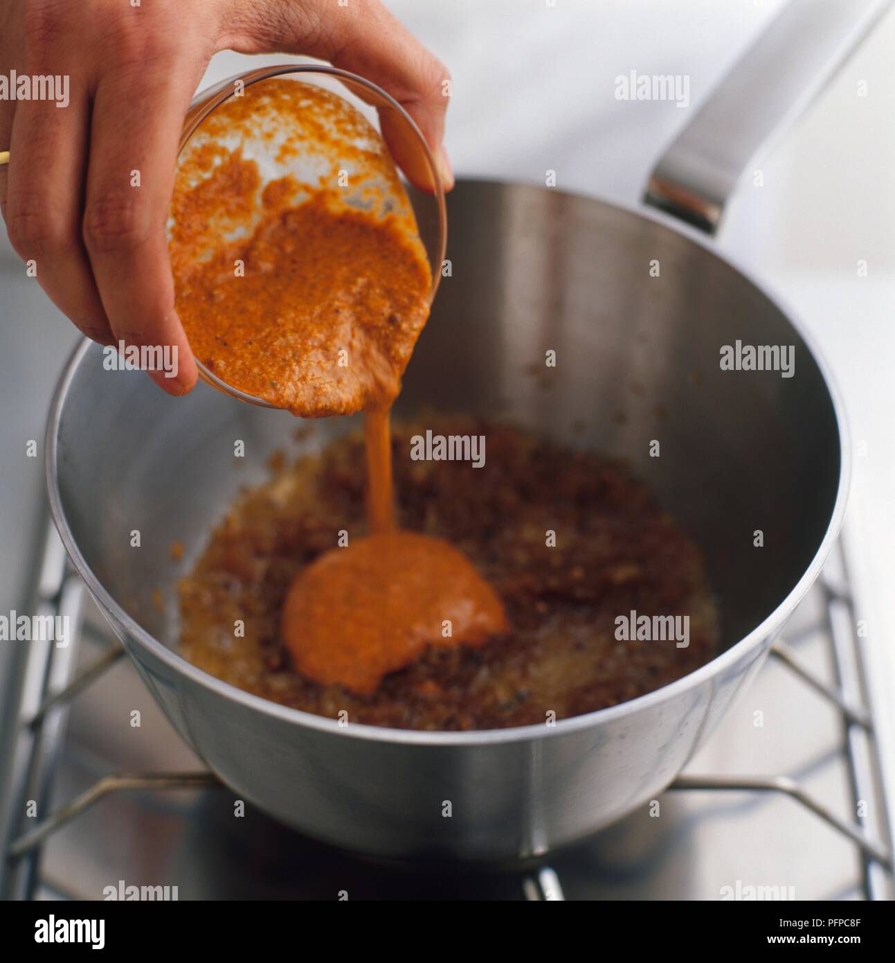 Pouring curry paste from bowl into pan Stock Photo - Alamy