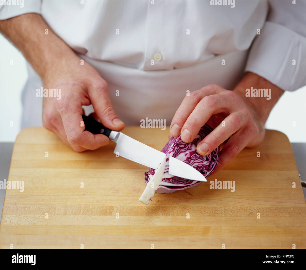Using kitchen knife to remove hard core from centre of red cabbage ...