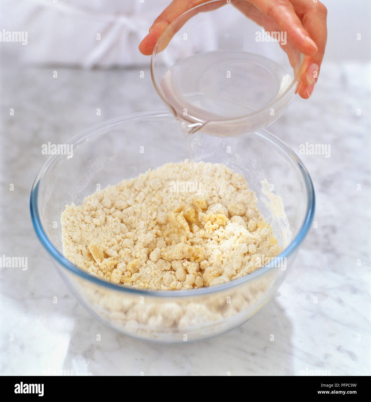 Pouring water over dry puff pastry in glass mixing bowl Stock Photo - Alamy