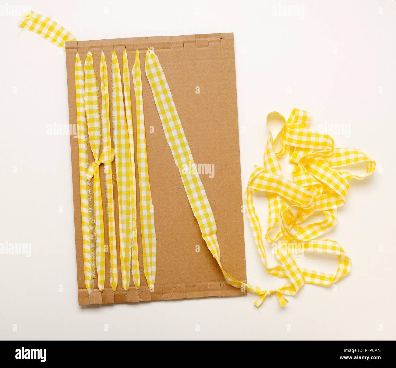 Strips of yellow gingham fabric threaded through slits in piece of ...