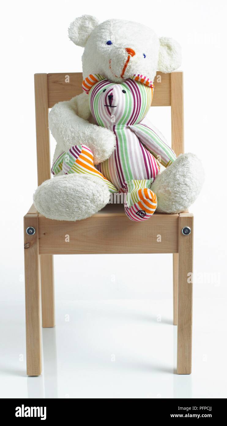 Striped teddy bear sitting on lap of white teddy bear who is sitting on ...