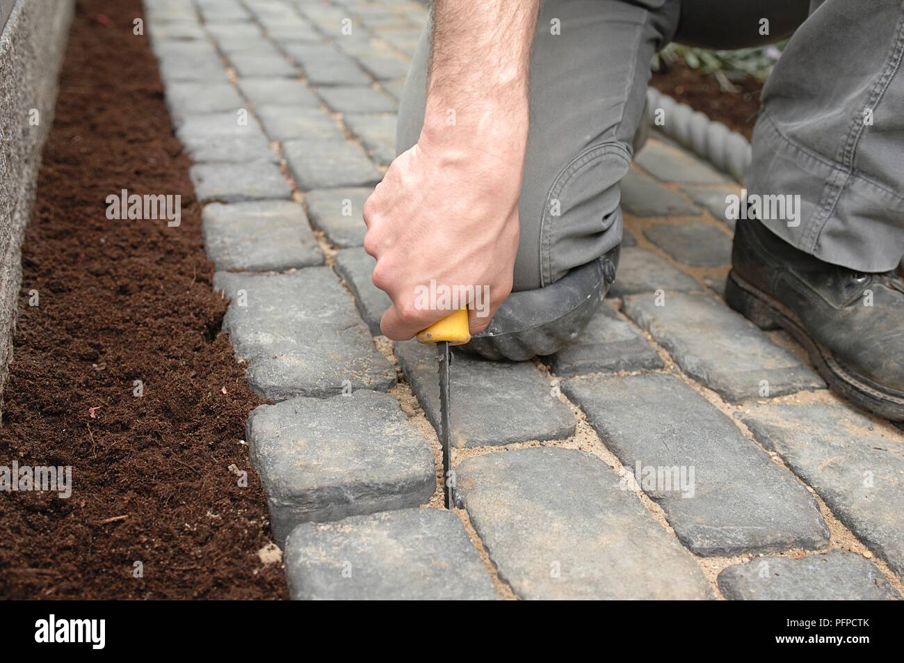 Man removing block from brick path to form planting pocket, close-up ...