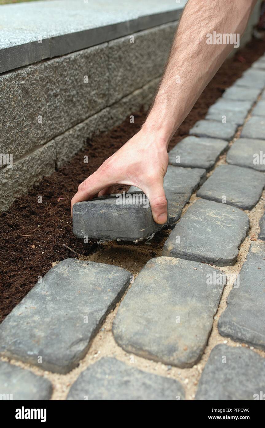 Man removing block from brick path to form planting pocket, close-up ...