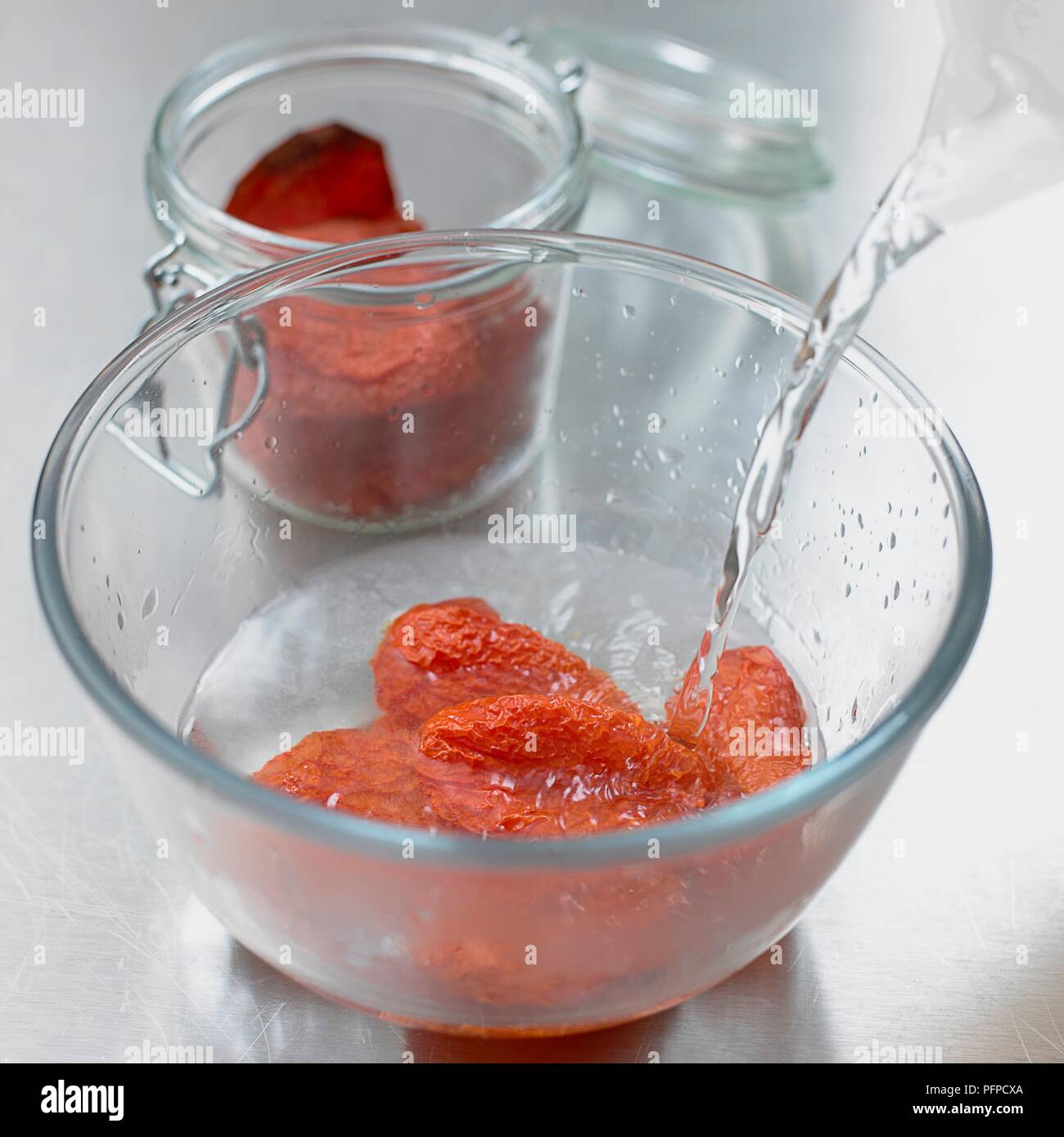 Pouring hot water on dried tomatoes in bowl to rehydrate Stock Photo ...