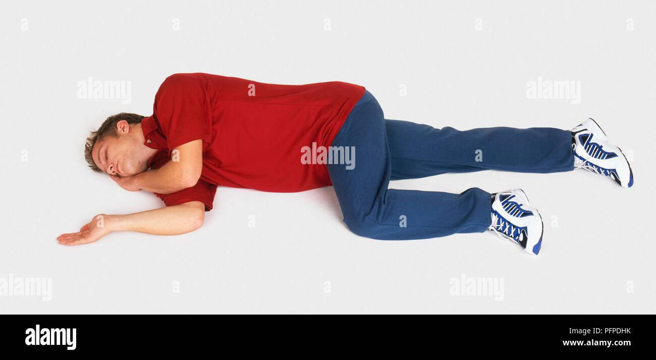 Young man lying on side in the recovery position Stock Photo - Alamy