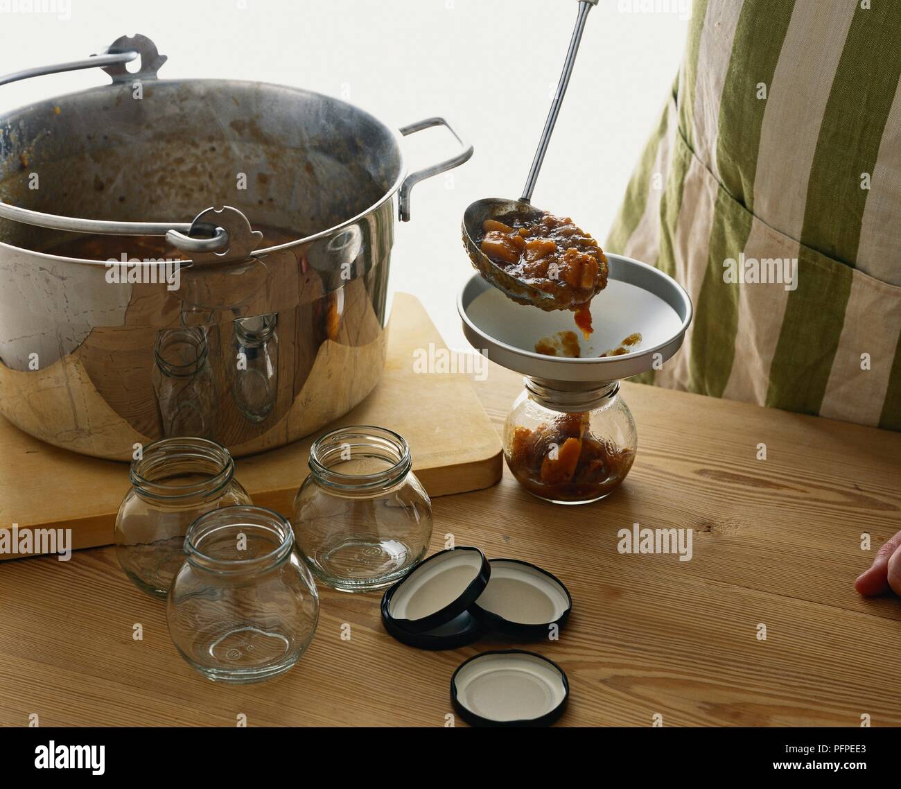 Ladling hot chutney into jar through funnel on wooden worktop Stock ...