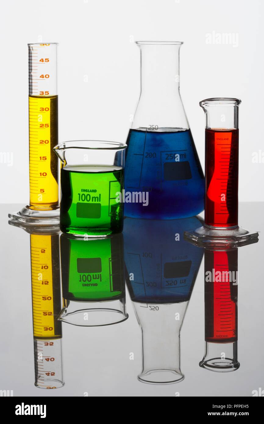 Glass beakers and measuring tubes containing different coloured liquids ...