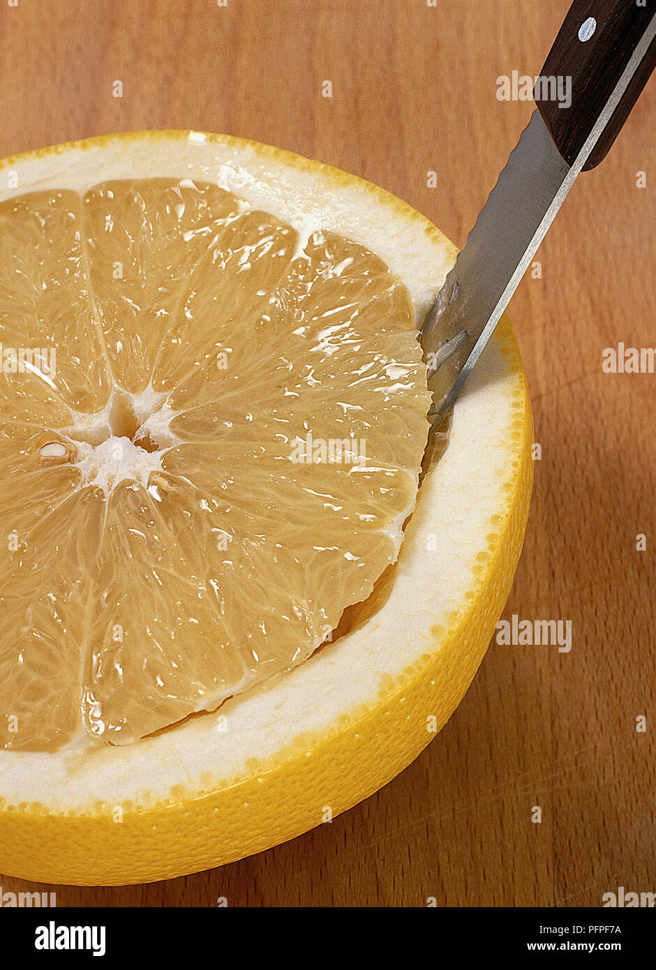 Segmenting a grapefruit, cutting out the flesh with a serrated knife ...