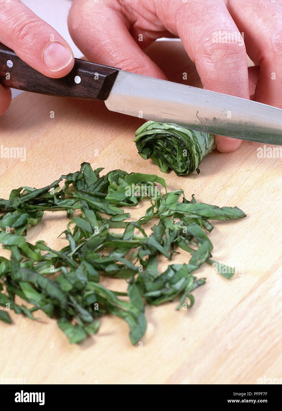 Shredding basil, rolled leaves being cut with a knife Stock Photo - Alamy