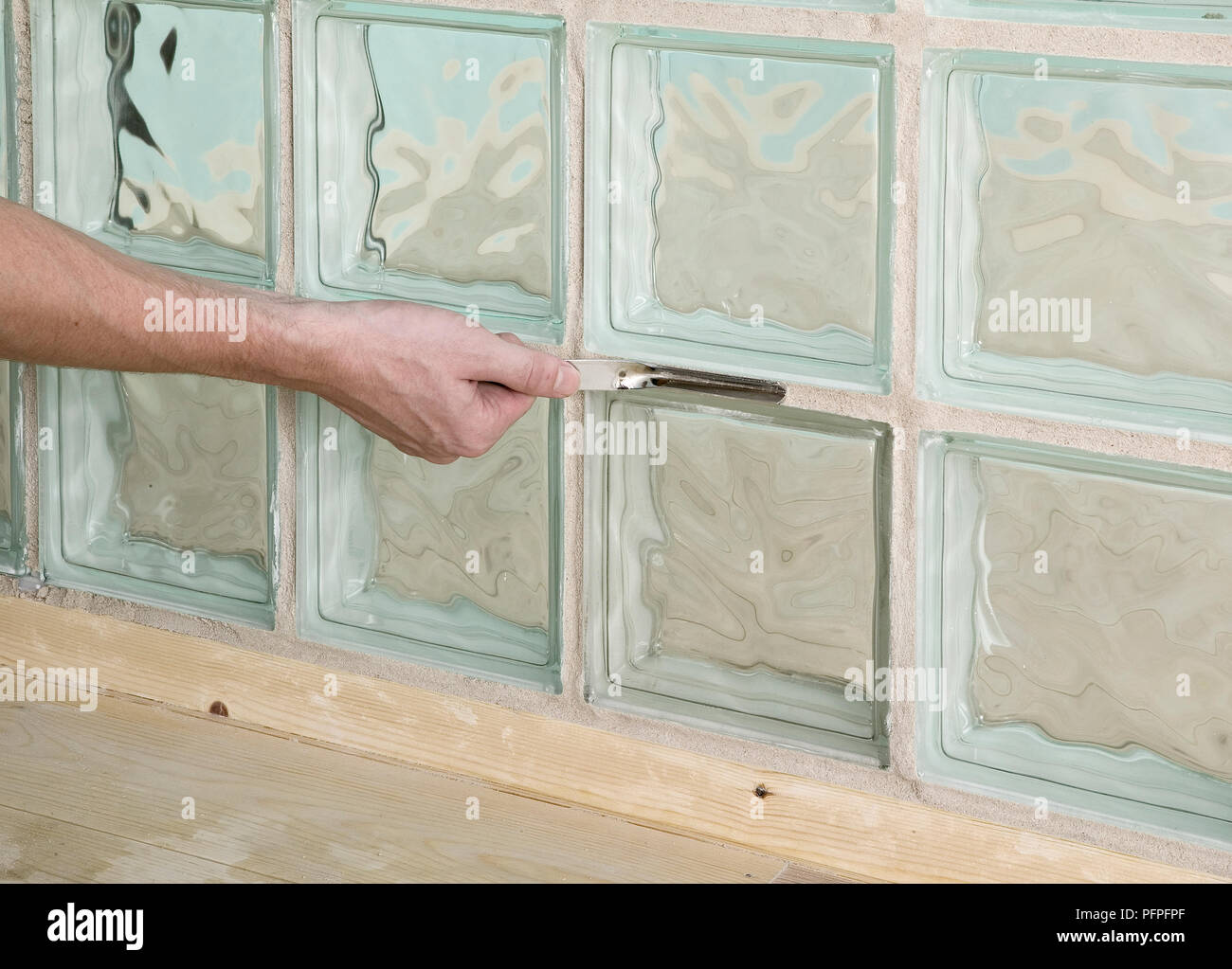 Man using grout smoother on small glass windows in wooden frame Stock ...