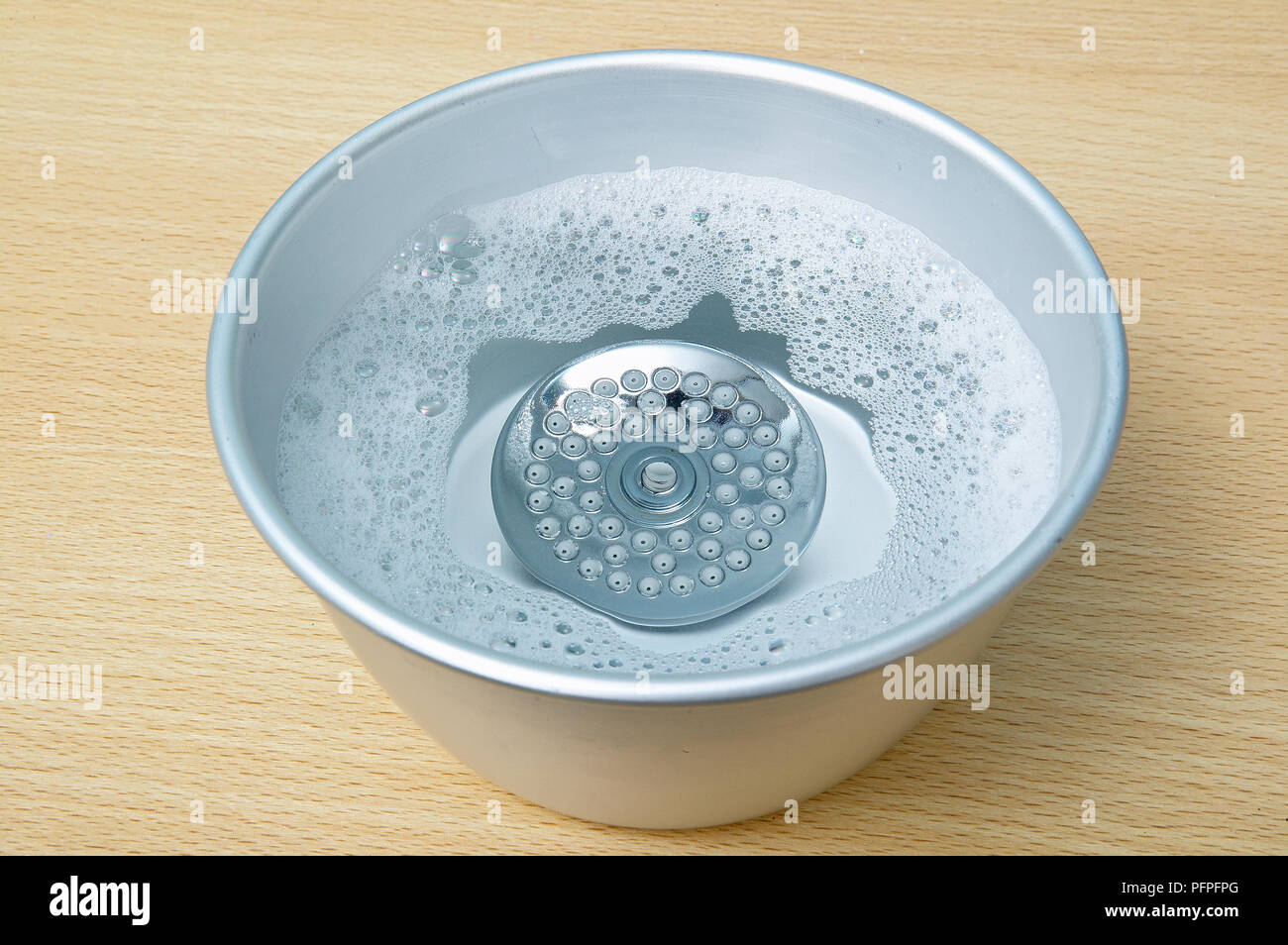 Shower head soaking in solution in metal bowl to remove hard water ...