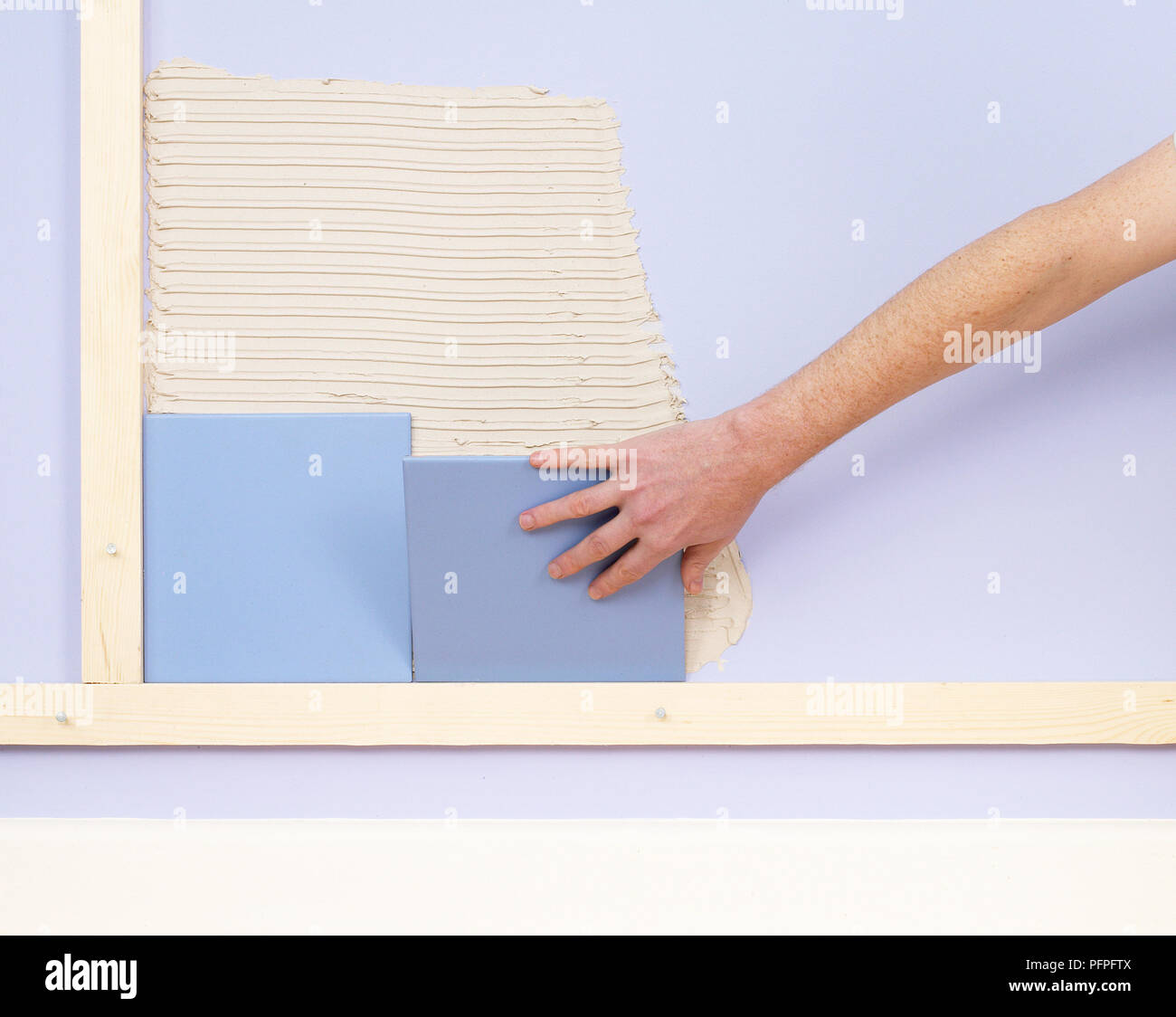 Hand placing tile on wall with adhesive Stock Photo - Alamy