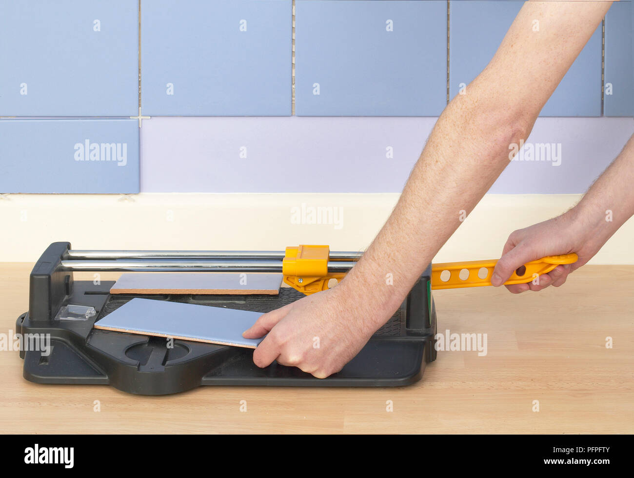 Hand holding cut tile in tile cutter Stock Photo - Alamy