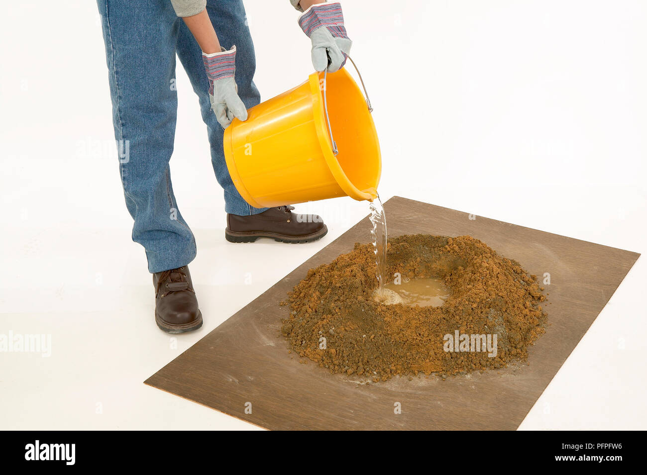 Pouring water from a bucket into the centre of dry cement mix Stock ...