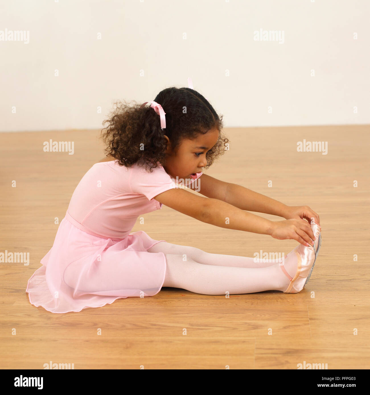 Girl in ballerina outfit sitting on floor and touching her toes, 4 ...