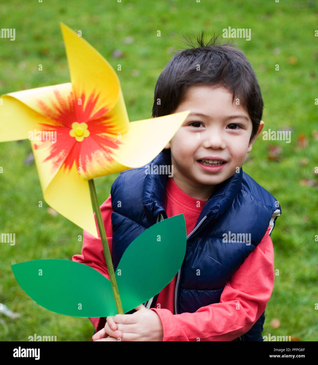 Boy holding pinwheel flower, looking at camera Stock Photo - Alamy