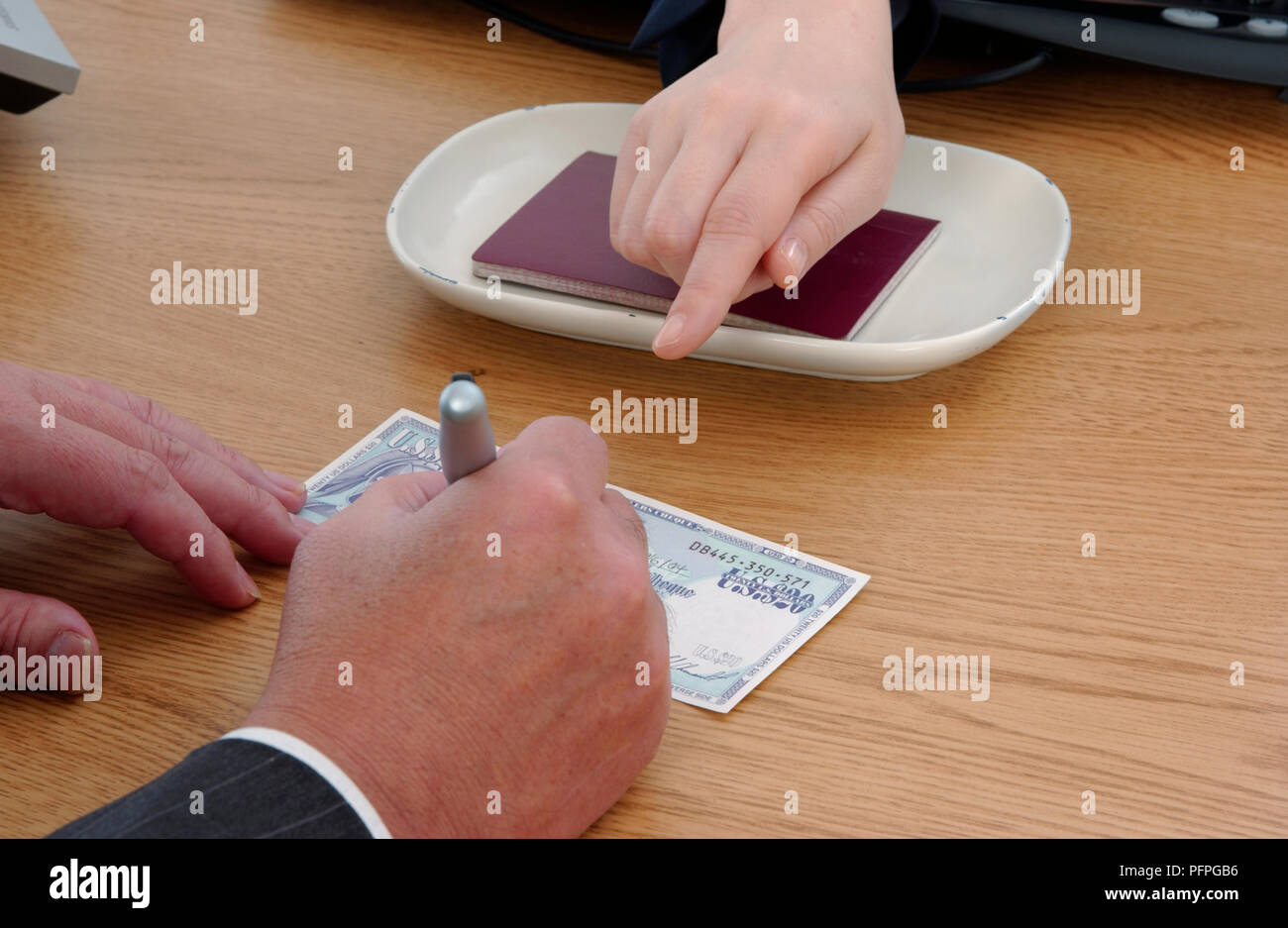 Man signing cheque at point indicated by woman Stock Photo - Alamy