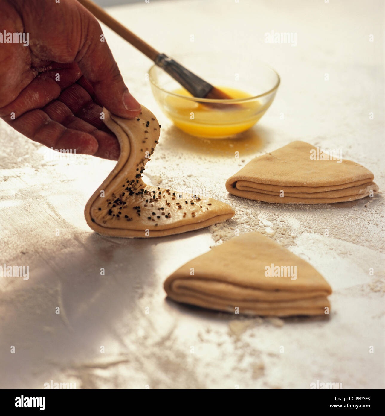 Making Tawa paratha triangular breads, sprinkled with black onion seeds ...