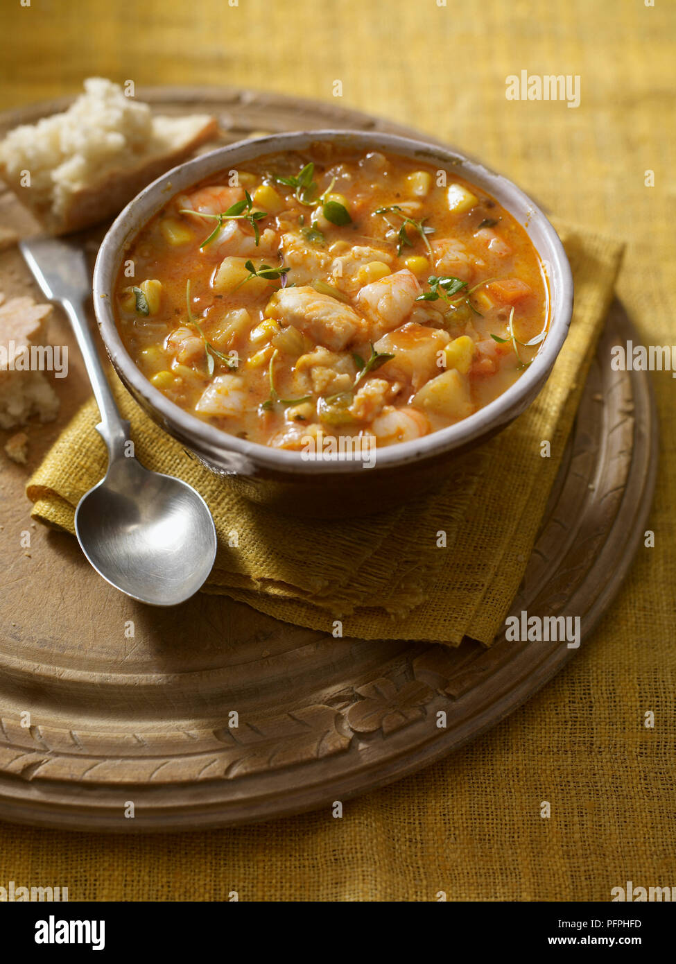 Creole fish and corn stew served in bowl with spoon on folded napkin ...