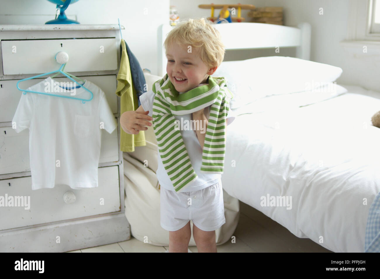Boy putting on stripy jumper Stock Photo - Alamy