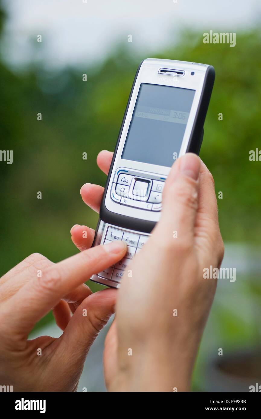 Hands holding mobile phone and using keypad Stock Photo - Alamy