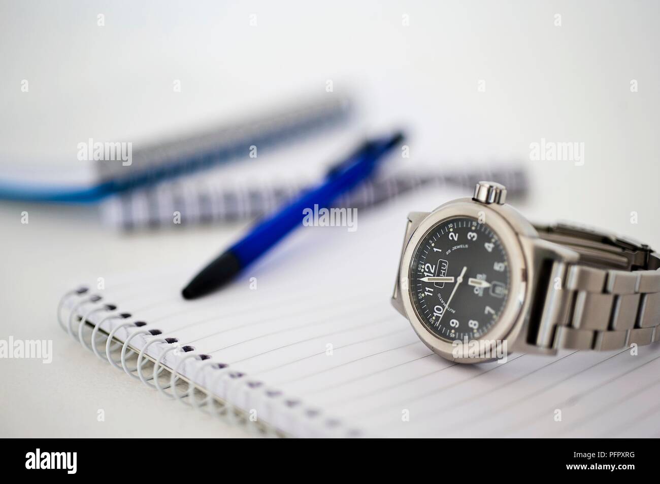 Man's wrist watch, spiral notebooks, and pen Stock Photo - Alamy