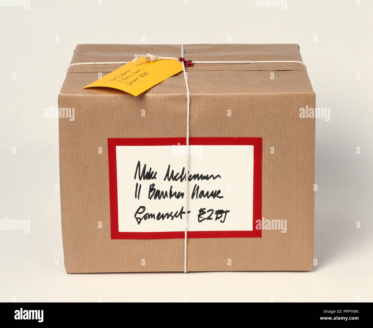A brown parcel, labelled and tied up with string Stock Photo - Alamy