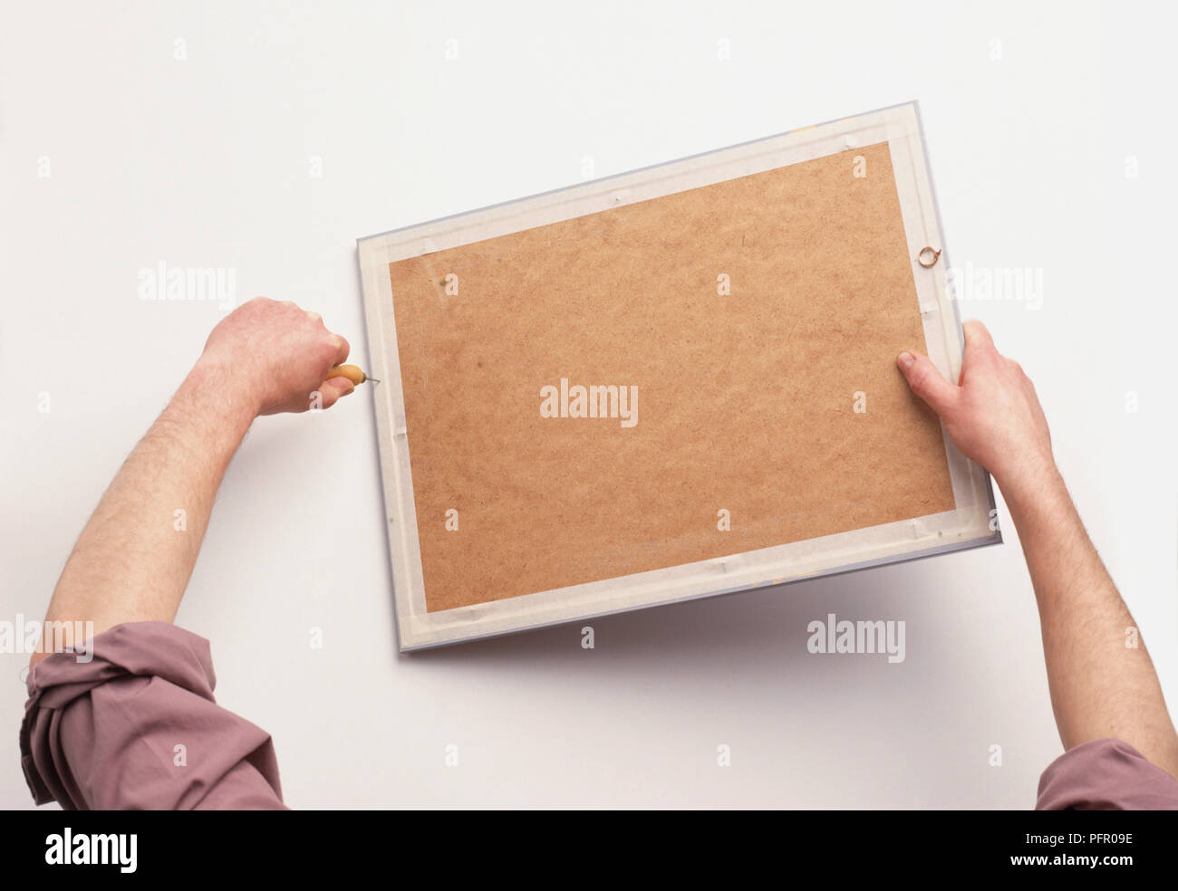 Man making holes in picture frame using an awl Stock Photo - Alamy
