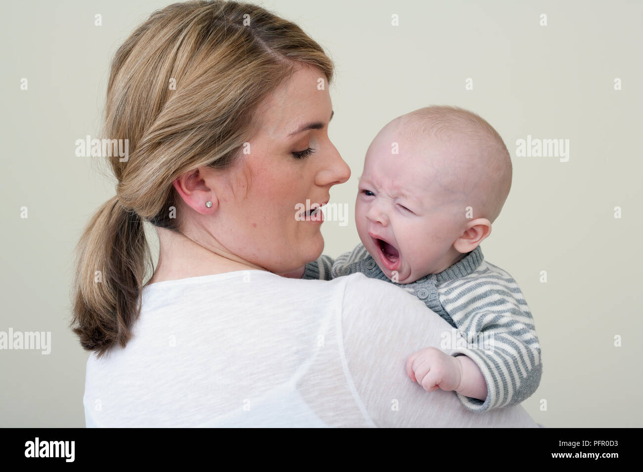 Woman holding yawning baby boy Stock Photo - Alamy