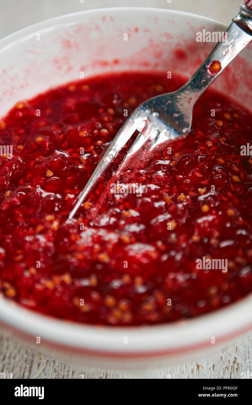 Crushed redcurrants and raspberries in bowl with fork Stock Photo - Alamy