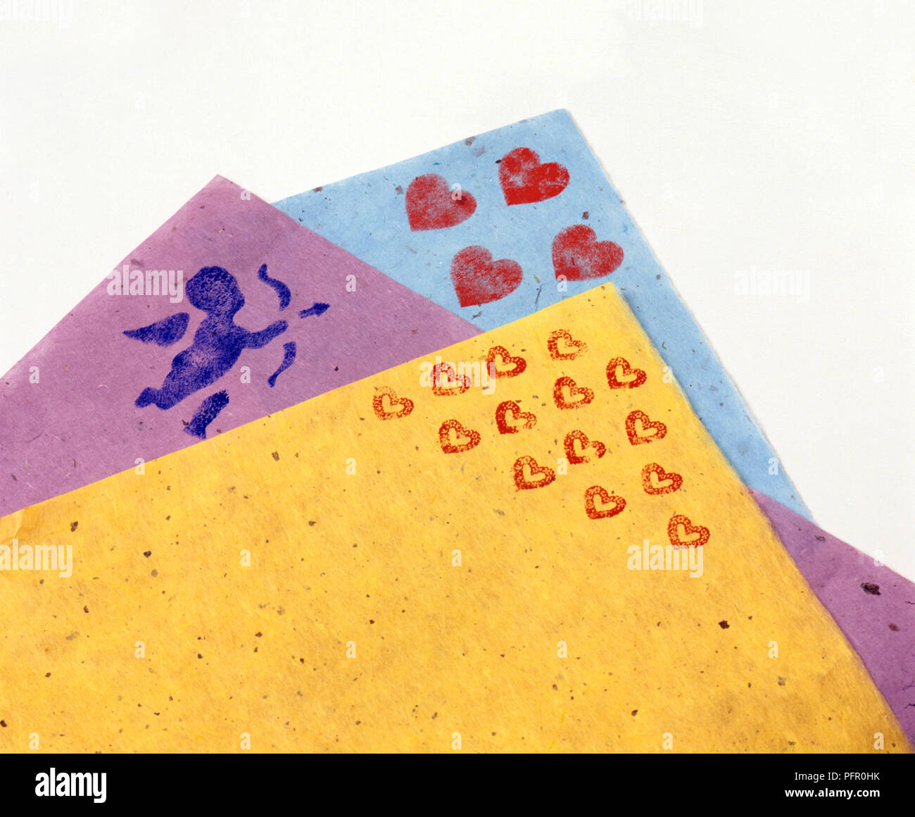 Handmade coloured paper with Cupid and heart shape patterns in corners ...