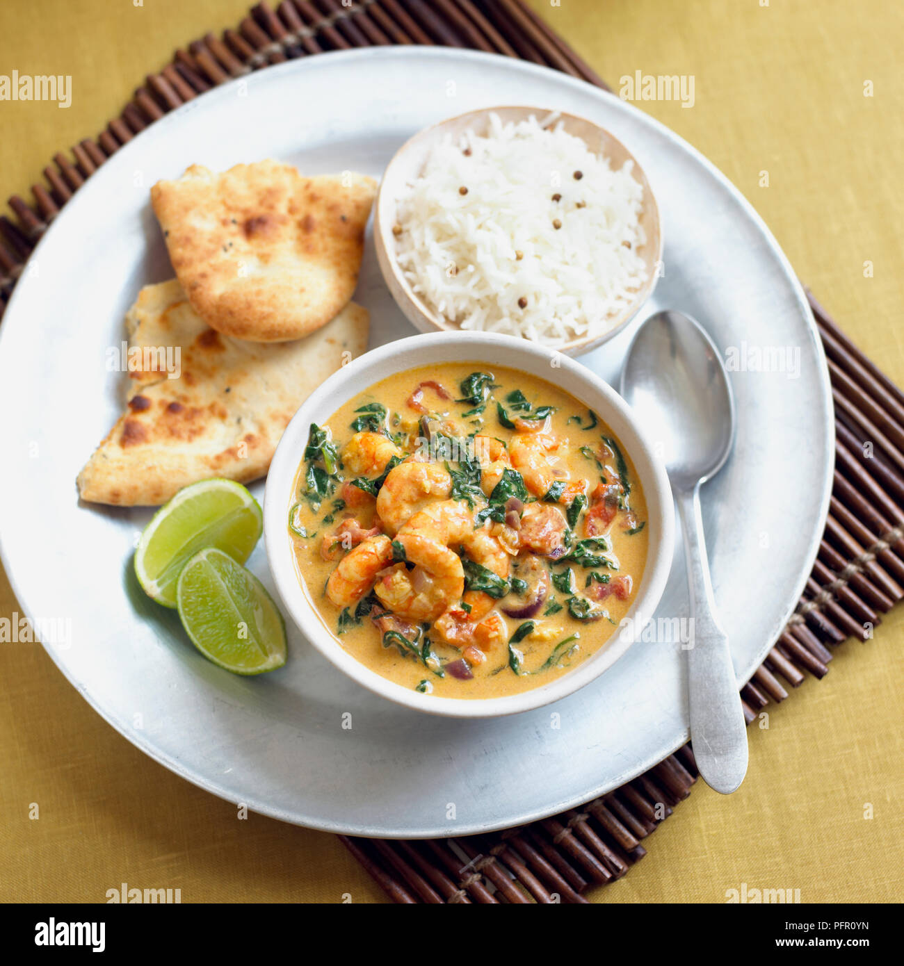 Spinach, tomato and prawn curry, with rice, naan bread and lime Stock ...