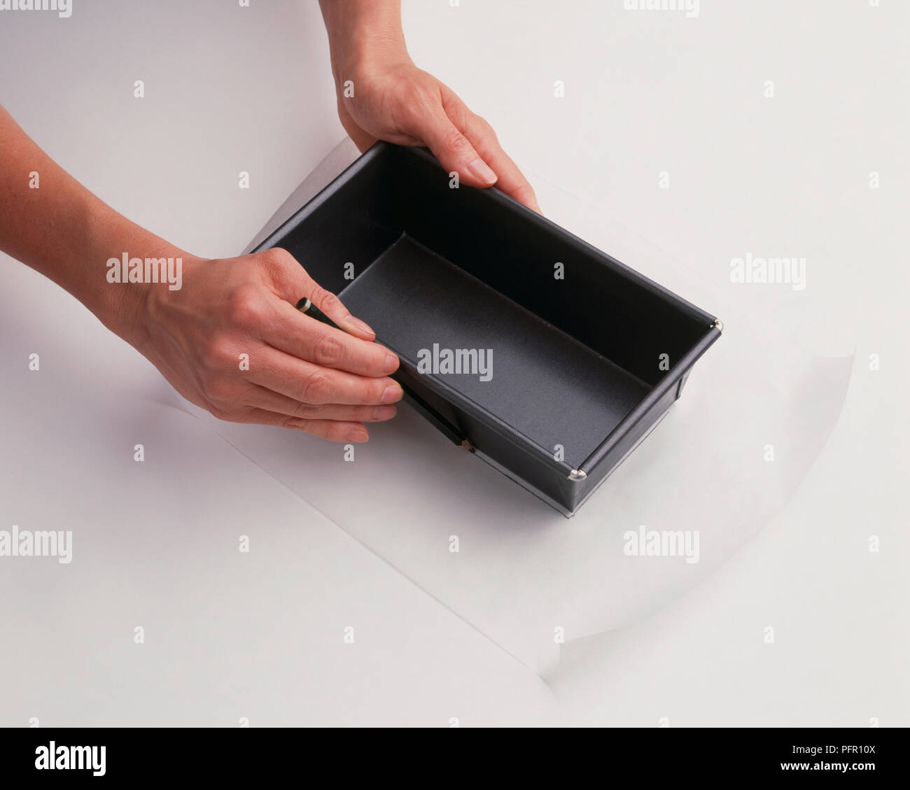 Person using pencil to draw outline of cake tin on wax paper, close-up ...