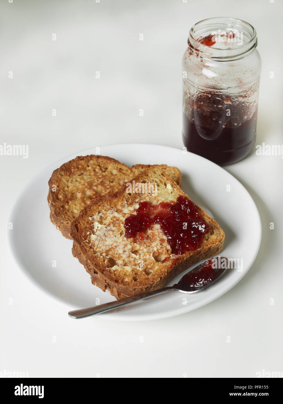 Jar of home-made jam and gluten-free bread spread with butter and jam ...