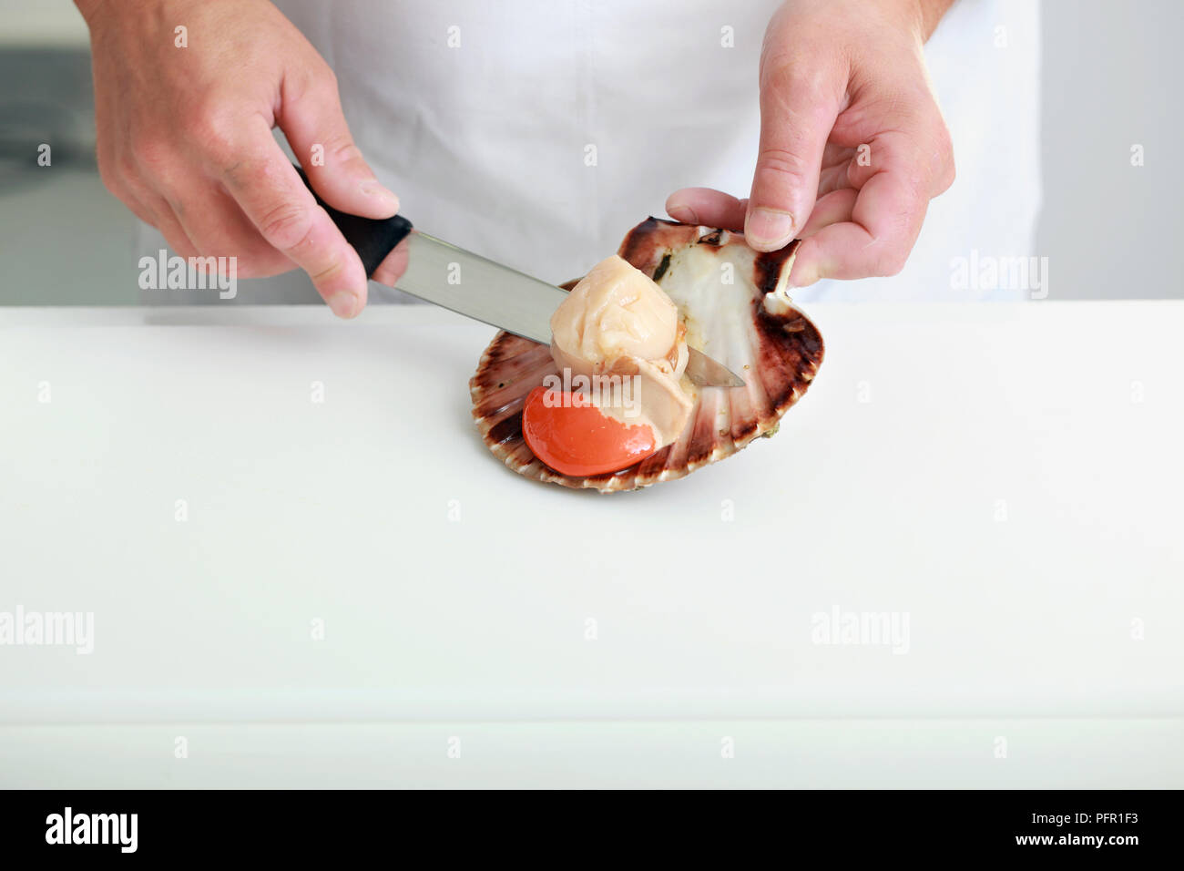 Preparing scallops, cutting scallop free from shell Stock Photo - Alamy