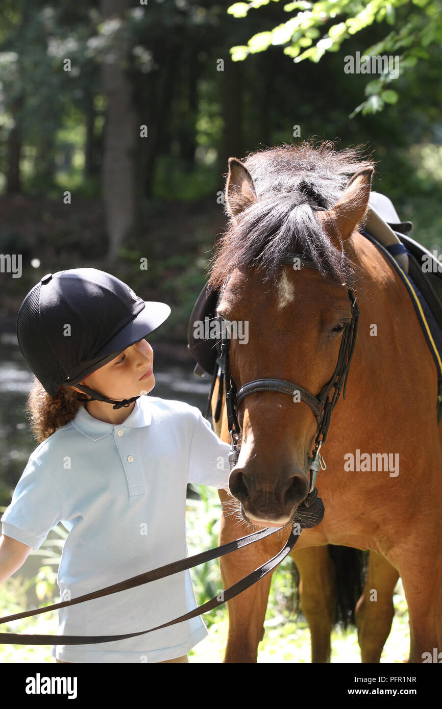 Girl holding horse by the bridle, close-up Stock Photo - Alamy