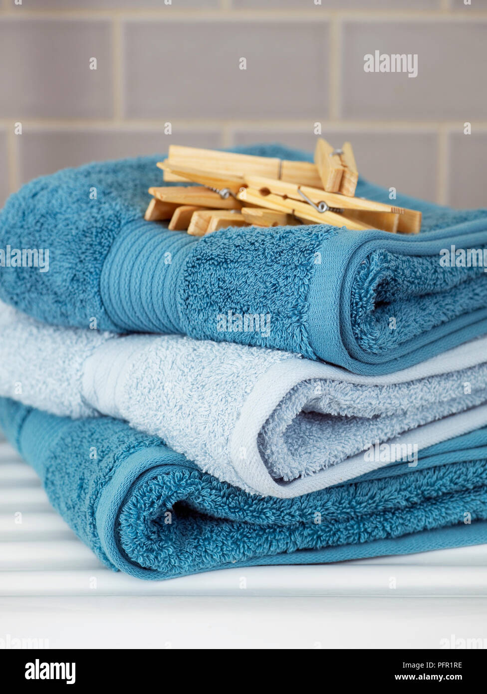 Wooden clothes pegs on top of stack of folded turquoise and pale blue ...